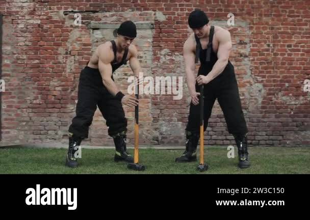 Two young muscular people train and do extreme exercises with a ...
