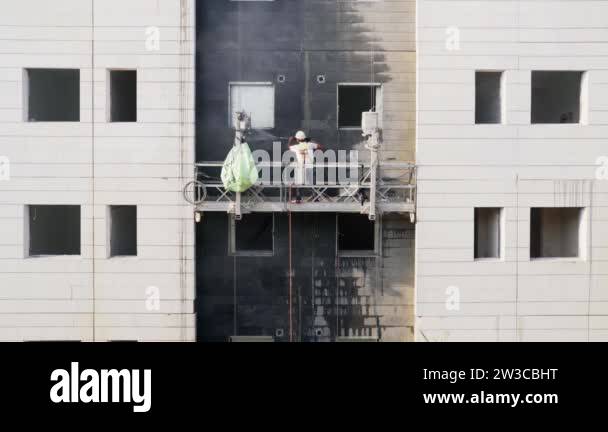 Construction worker cleans a wall of building using a high-pressure ...