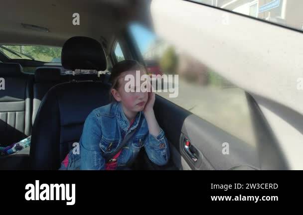 ored girl rides in the car and looks at the window. Girl with sad face ...