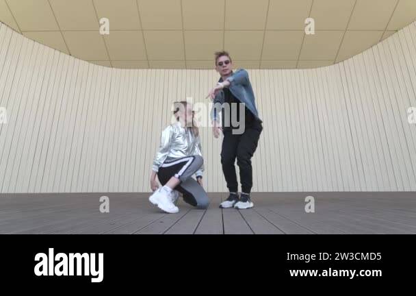 shooting from a low point of duet of young dancers dancing street break ...