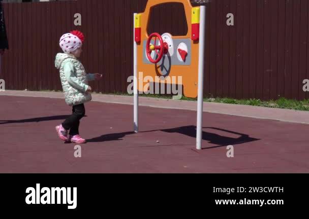 Little beautiful girl plays on a modern playground with her mom. Sunny ...