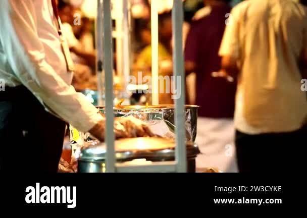Waiters serving food to a line of people at a south Indian wedding in ...