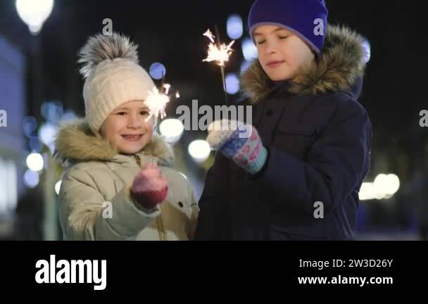 Two cute young children, boy and girl in warm winter clothing holding ...