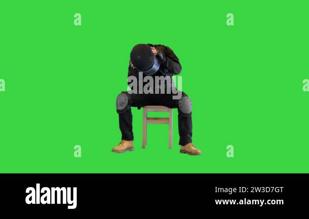 Riot policeman sitting with helmet off having rest on a Green Screen ...