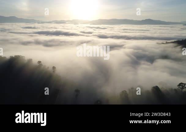 White clouds of dense fog move flowing over mountain Sunrise or sunset ...