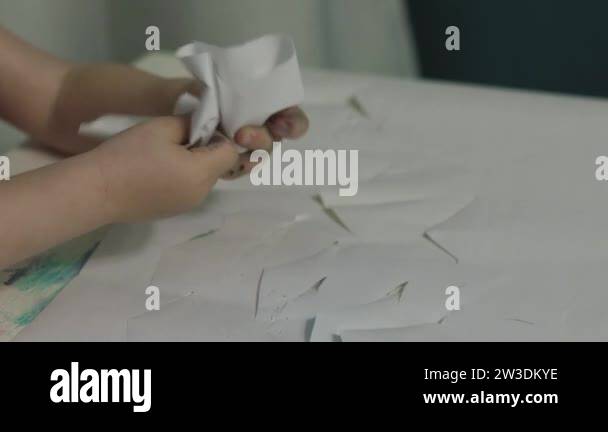 Caucasian Child squeezes a white sheet of paper into a lump. Close-up ...