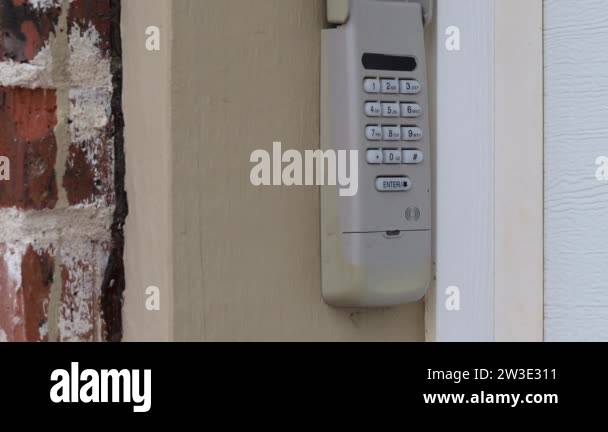 Hand entering secret code on Keypad used on a garage door entrance to a ...