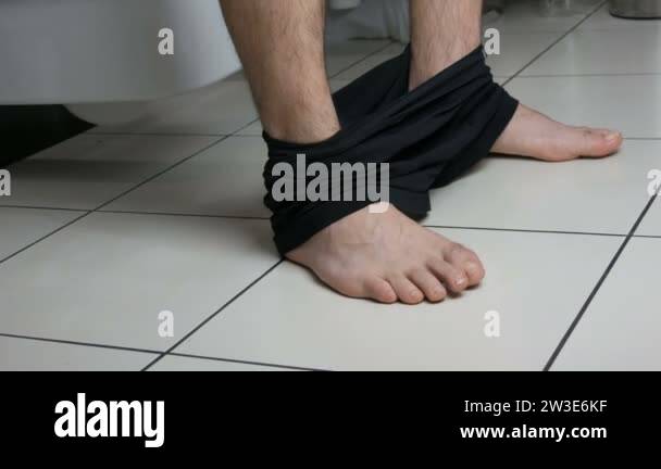 Legs of a man sitting on the toilet in the bathroom. Defecation process ...