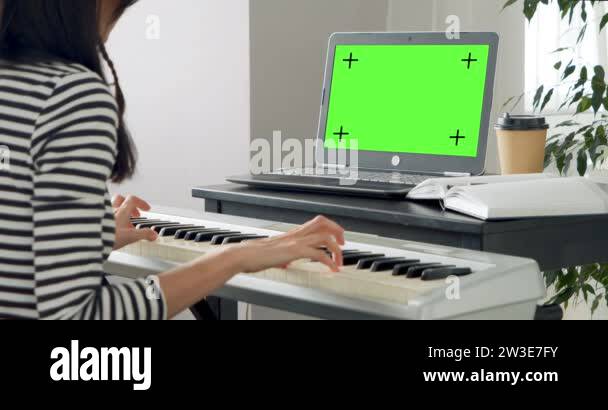 Young woman playing electronic piano learning remotely using a laptop ...