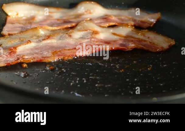 Fry the bacon in a pan. A slice of pork bacon is prepared in its own ...