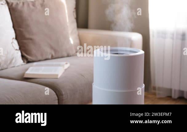 Woman pouring water from the filter to air humidifier, aroma oil diffuser at home. Improving the ...