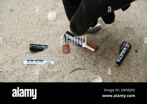 Man collect electronic battery waste on sandy sea coast ecosystem ...