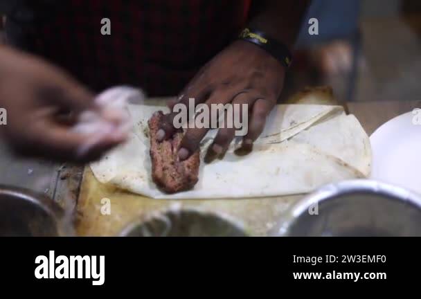 Man wrapping mutton seekh kabab in rumali roti, Indian bread. Mutton ...