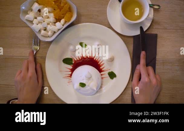 Man eating a dessert of meringue with knife and fork. Persons hands ...