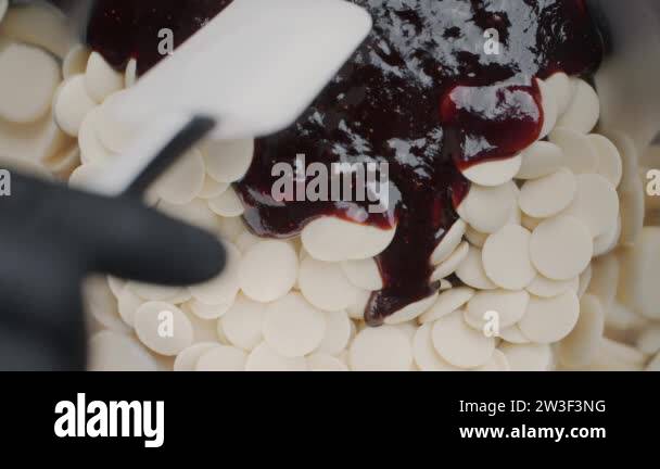 Tabletop video: confectioner is mixing hot strawberry jam and white ...