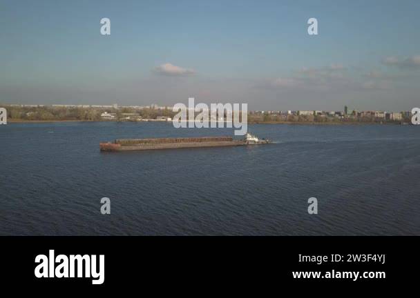A tugboat ship pushes a barge upstream of the river to transport bulk ...