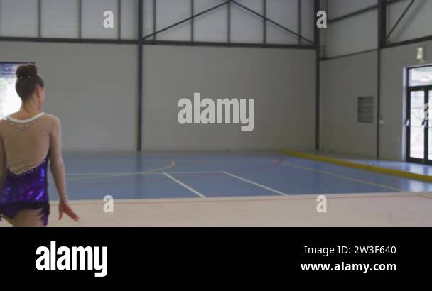 Rear view of focused teenage Caucasian female gymnast performing at ...