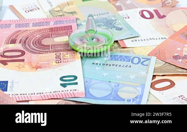 the rotation of a plastic whirligig on a pile of euro banknotes as a ...