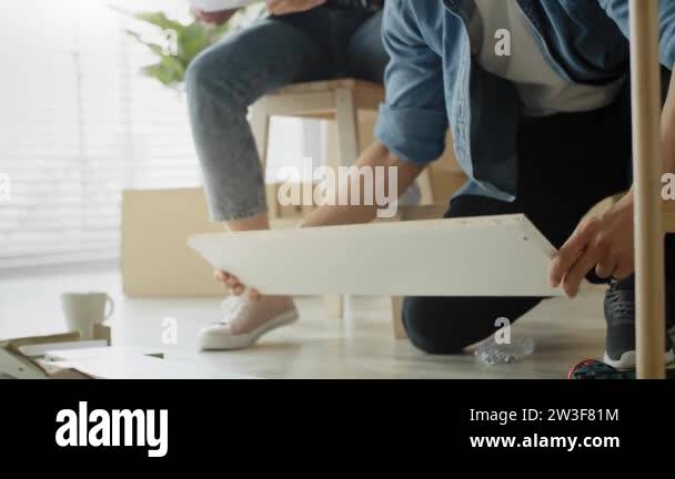 Tracking video of couple checking manual before installing furniture ...