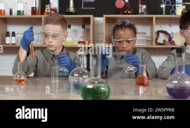 Laboratory experience in a chemistry lesson, kids in protective glasses ...