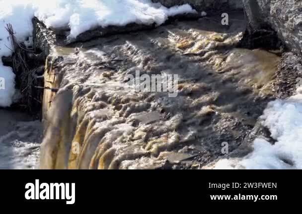 Thawed, dirty water with garbage cascades into the reservoir on a ...