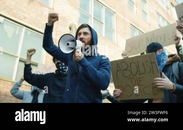 Caucasian young man leader screaming mottos in megaphone at street in ...