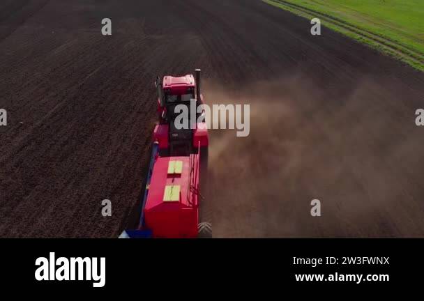 Agricultural works, red tractor, plough with rakes furrows the field ...