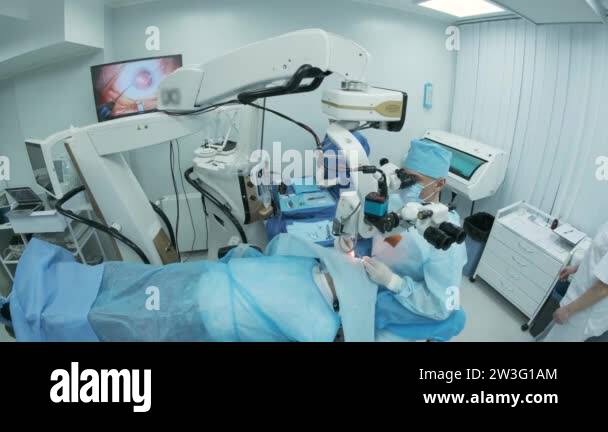 Surgeon looking into the microscope at the eye of female patient at the ...