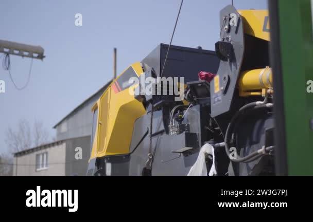 Loader holding heavy equipment on factory with Caucasian workers ...