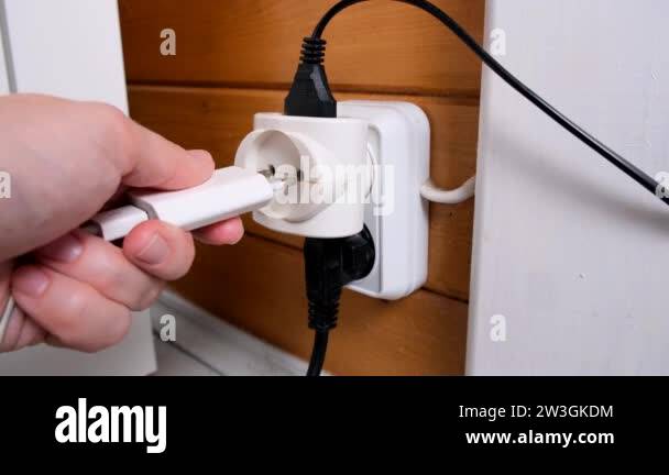 Overloaded outlet with an extension and many sockets plugged in, a hand ...