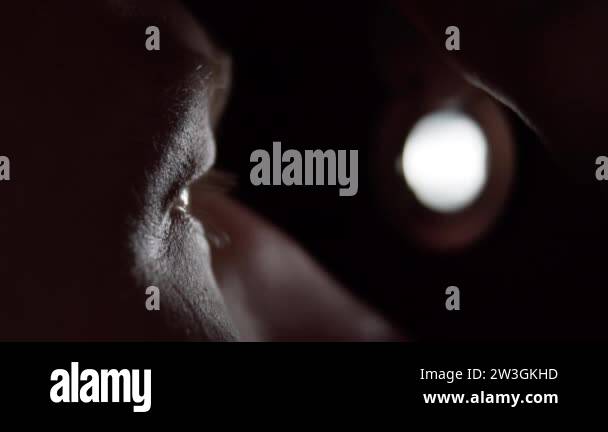 Male eye looking through the peephole, watching what is going on behind ...