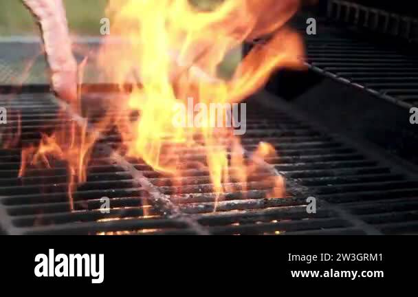 Man roasts meat on grill. chef uses tongs to place piece of raw juicy ...