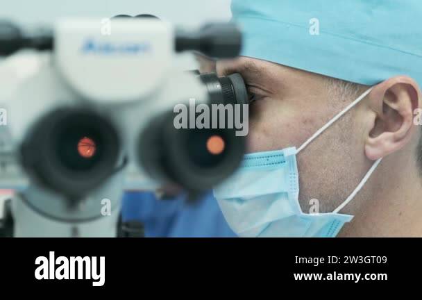 Surgeon looking into the microscope at the eye of female patient at the ...