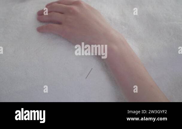 Close-up of young female Caucasian hand with needle inserted lying on ...