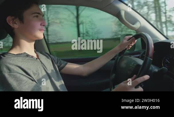 Young man drives the car at first time. Novice driver is driving a car ...