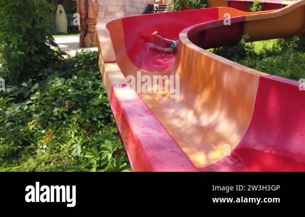 Boy slide on slider in water park on summer holiday. Happy boy sliding ...