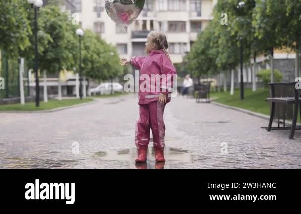 Wide shot of positive little girl posing with balloon as standing in ...