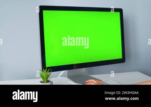 Woman typing on a computer keyboard, monitor with a green screen ...