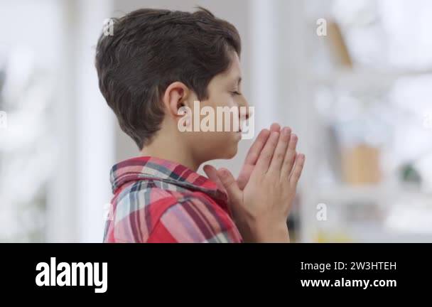 Side view close-up of little Middle Eastern boy praying with hands ...