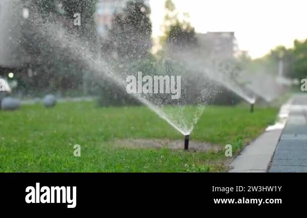 Irrigation water sprinklers in front of a modern building. The ...