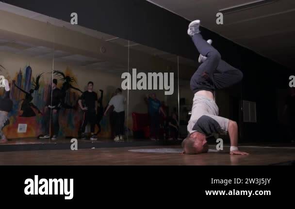 Young guy making swipes, windmills and dancing at gym studio in slow ...