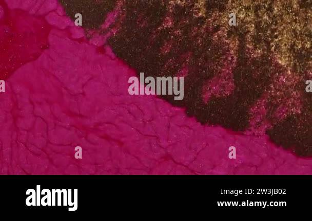 A stream of pink liquid paint with particles of silver sparkles. It ...