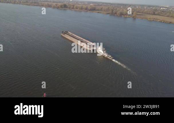 A tugboat ship pushes a barge upstream of the river to transport bulk ...
