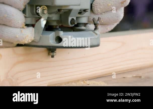 Joiner cuts off the sharp corners of a wooden beam using a milling ...