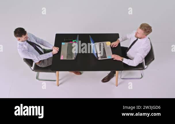 Good looking two office workers sitting on the same table in a white ...