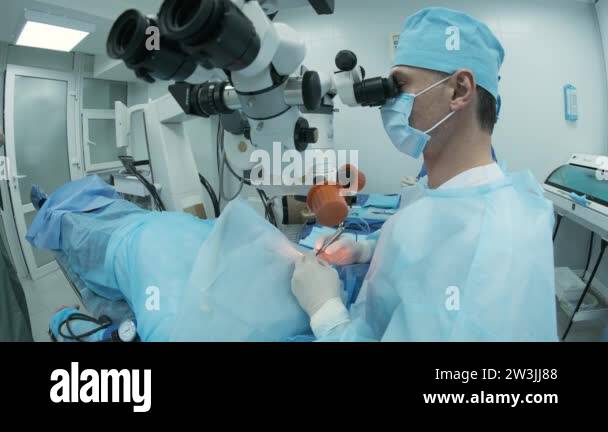 Surgeon looking into the microscope at the eye of female patient at the ...