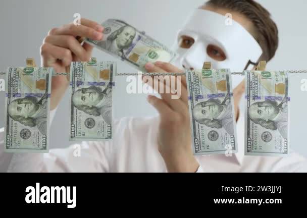Masked anonymous laundering money. Dollars dry on clothespin rope. The ...
