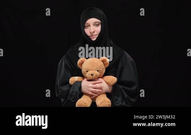 Middle shot portrait of shy Muslim woman in hijab posing at black ...