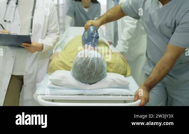 Tilt up shot of team of paramedics giving ventilation to emergency ...