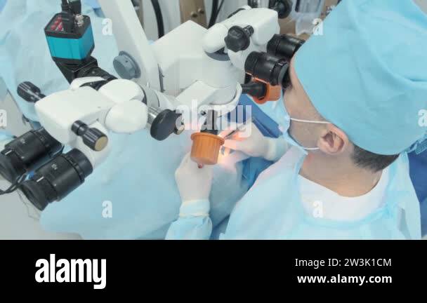 Surgeon looking into the microscope at the eye of female patient at the ...